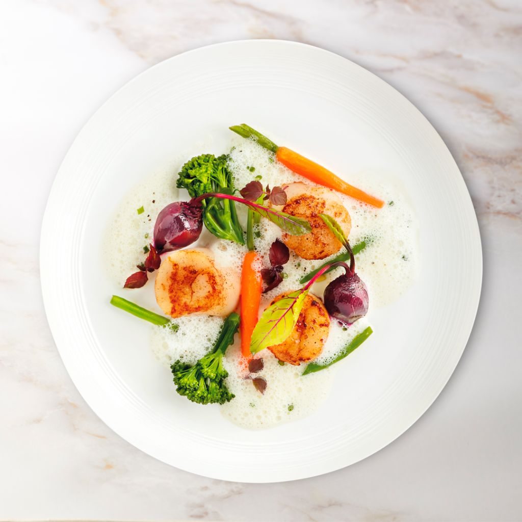 Sint-Jakobsnoten en groenten gebakken in gebruinde boter met een saus ...